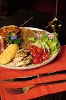 Um prato de comida com pão, salada, tomates, cogumelos e uma omelete.