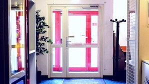 Um corredor com uma porta dupla, uma planta e um cabide.