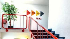 Uma escadaria com corrimão vermelho e setas indicativas nas paredes.