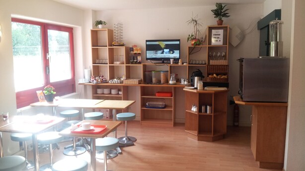 Cozinha compacta com armários de madeira, área de refeições com banquetas, televisão e diversos eletrodomésticos.