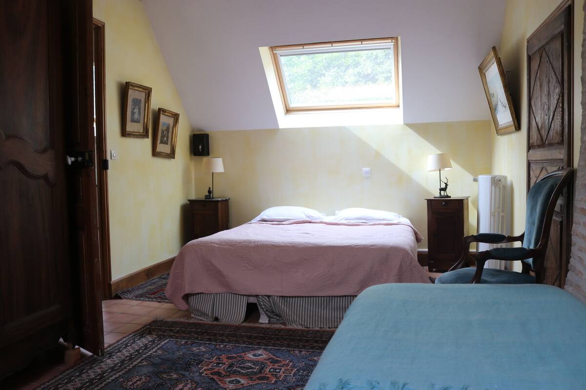 Um quarto com uma cama, uma cadeira, uma janela e uma porta.