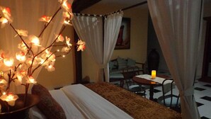 Quarto com cama, mesa de cabeceira com uma vela e uma planta decorativa.