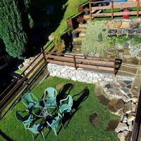 Uma área de pátio com muro de pedra, deck de madeira e um espaço de estar com cadeiras e mesa.