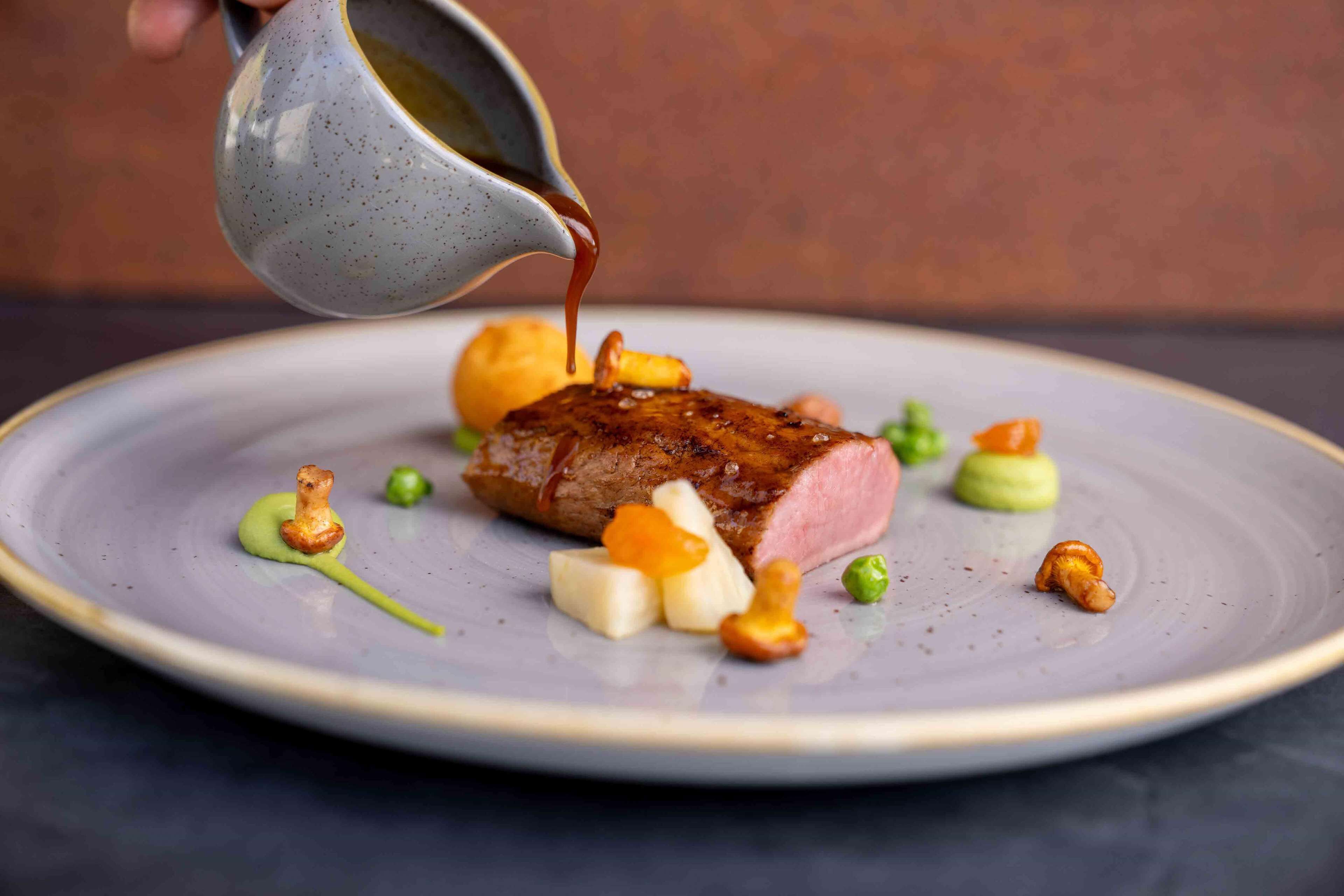 Um prato com carne, legumes e molho.