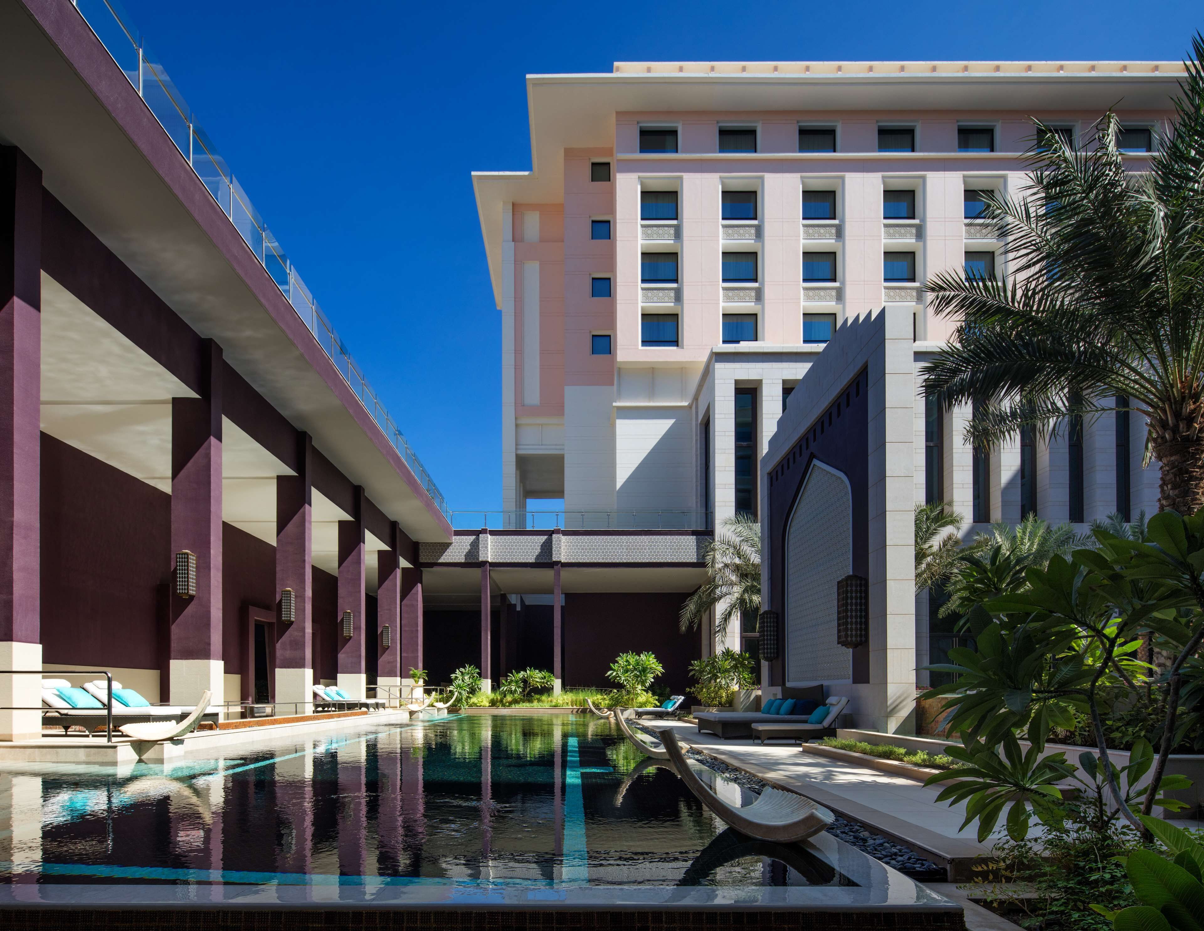 Um hotel moderno com piscina, áreas de estar e vista para a arquitetura do edifício.