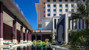 Um hotel moderno com piscina, áreas de estar e vista para a arquitetura do edifício.
