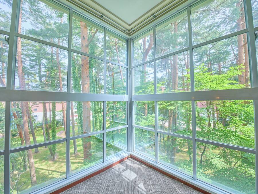 Quarto com grandes janelas e vista para uma floresta.