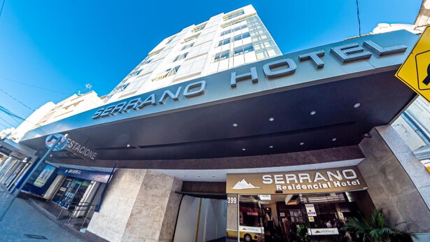 Exterior do Hotel Serrano, com entrada e sinalização destacadas.