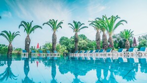 Piscina com espreguiçadeiras e palmeiras.