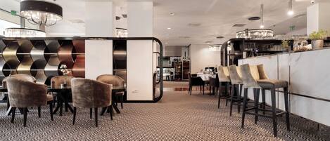 Um restaurante moderno com área de bar, piso de madeira e tapete estampado.
