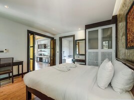 Quarto com uma cama grande, uma escrivaninha e uma cadeira. Dá para ver um banheiro por uma porta aberta.