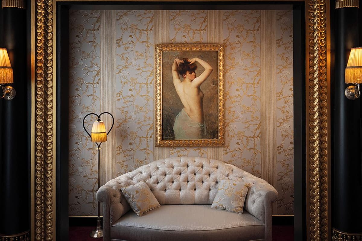 Um quarto luxuoso com sofá estofado, quadro emoldurado e painéis de parede ornamentados.