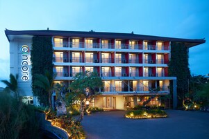 Um hotel de vários andares com fachada moderna, varandas e uma entrada bem iluminada.