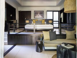 Quarto moderno com cama, sofá e uma mesinha de cabeceira.
