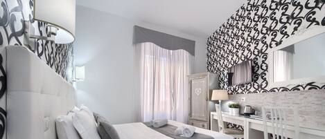 Quarto com cama, mesa de cabeceira, luminária, guarda-roupa e escrivaninha com cadeira.