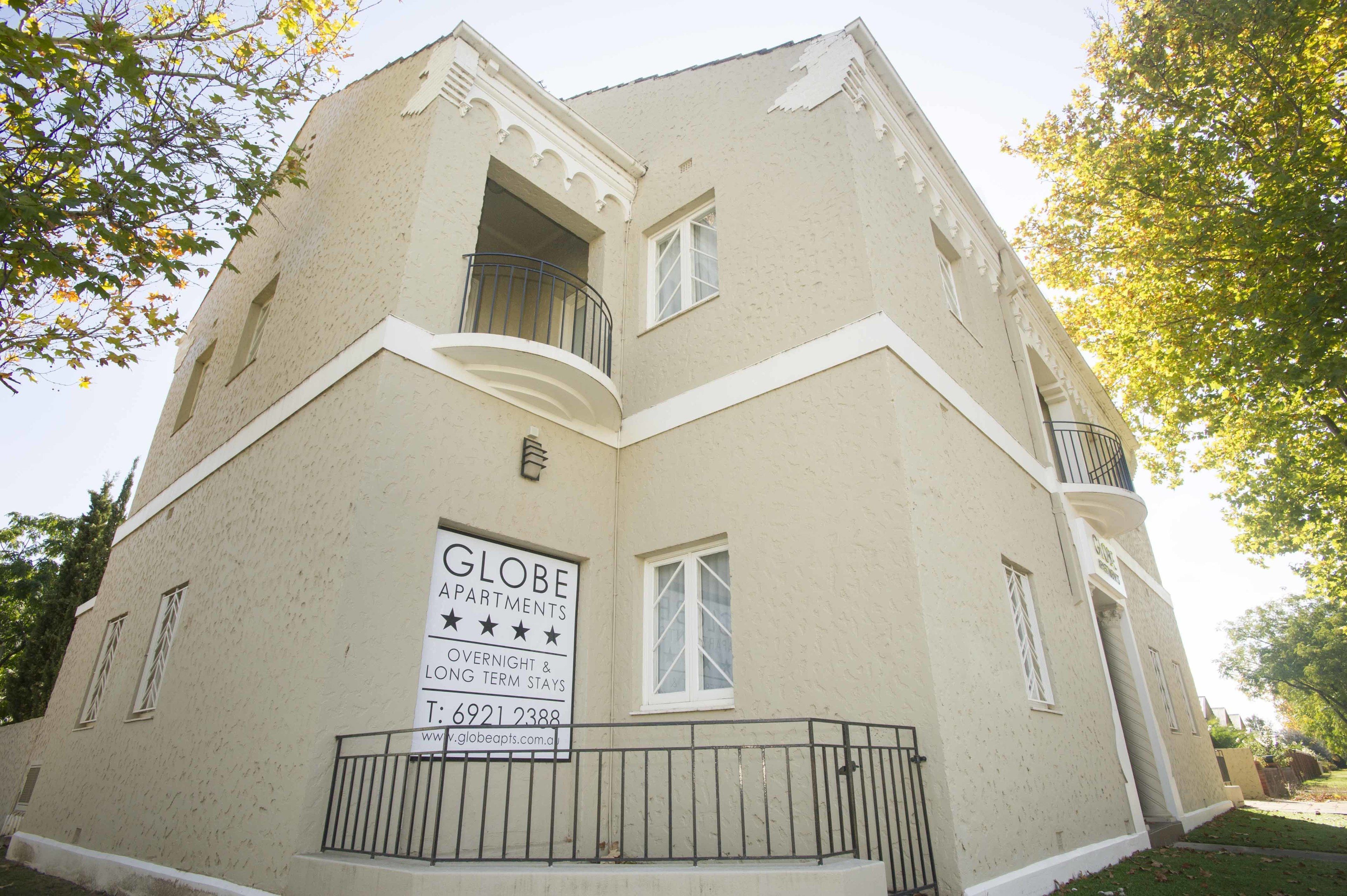 Um edifício com uma placa anunciando Globe Apartments, com estadias de curta e longa duração.