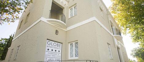 Um edifício com uma placa anunciando Globe Apartments, com estadias de curta e longa duração.