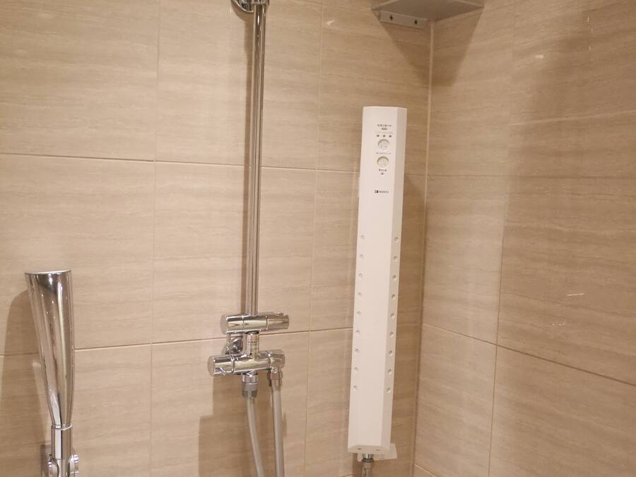 Chuveiro moderno com painel de controle, chuveiro manual e torneira manual.