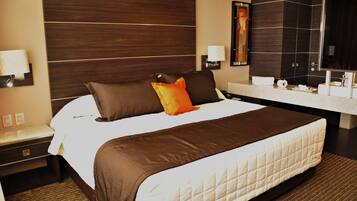 Quarto de hotel com uma cama grande, mesa de cabeceira, espelho no banheiro e porta-toalhas.