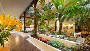 Um exuberante jardim interno com áreas de estar, plantas grandes e uma variedade de flores.