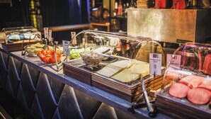Buffet com diversos pratos, incluindo uma saladeira, uma sopa e uma travessa de carnes fatiadas.