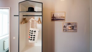 Um quarto com uma estante preta, uma luminária pendente e duas molduras na parede.