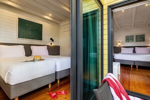 Quarto de hotel com duas camas, uma janela grande com vista e piso de madeira.