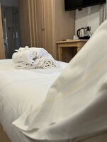 Cama bem arrumada com toalha dobrada e travesseiro.