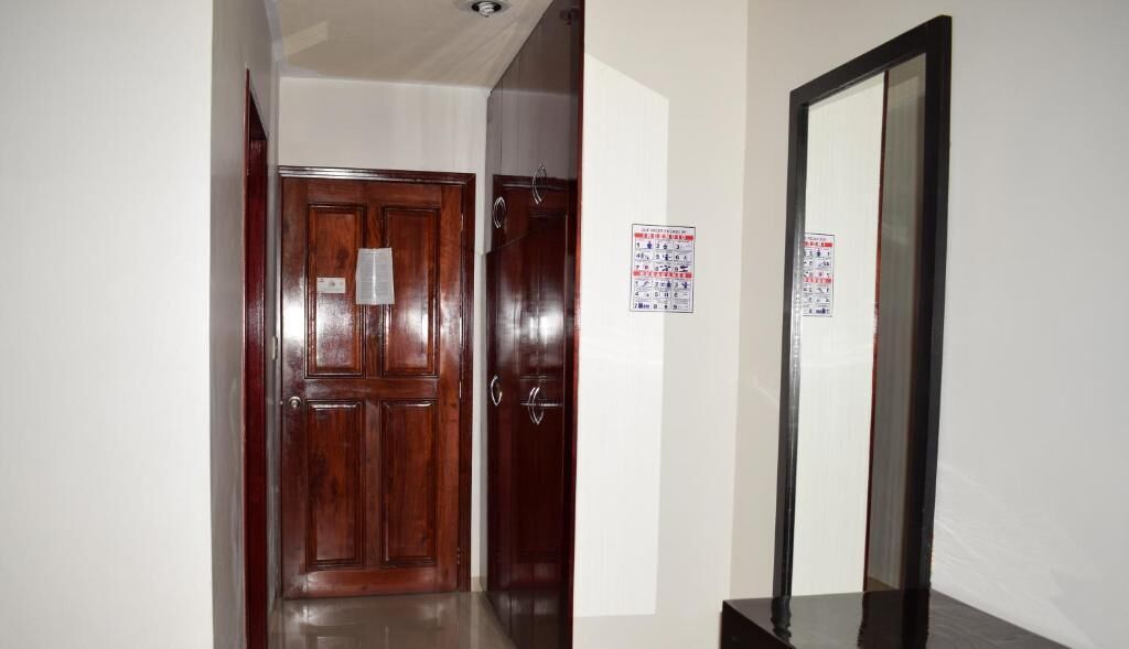 Um corredor com porta de madeira, espelho e um aviso na parede.