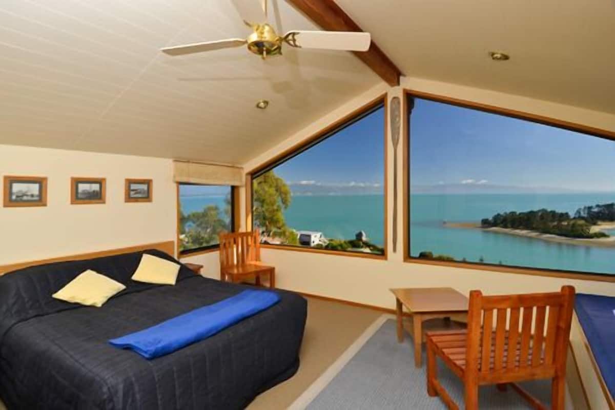 Quarto com cama grande, escrivaninha e vista para o mar.