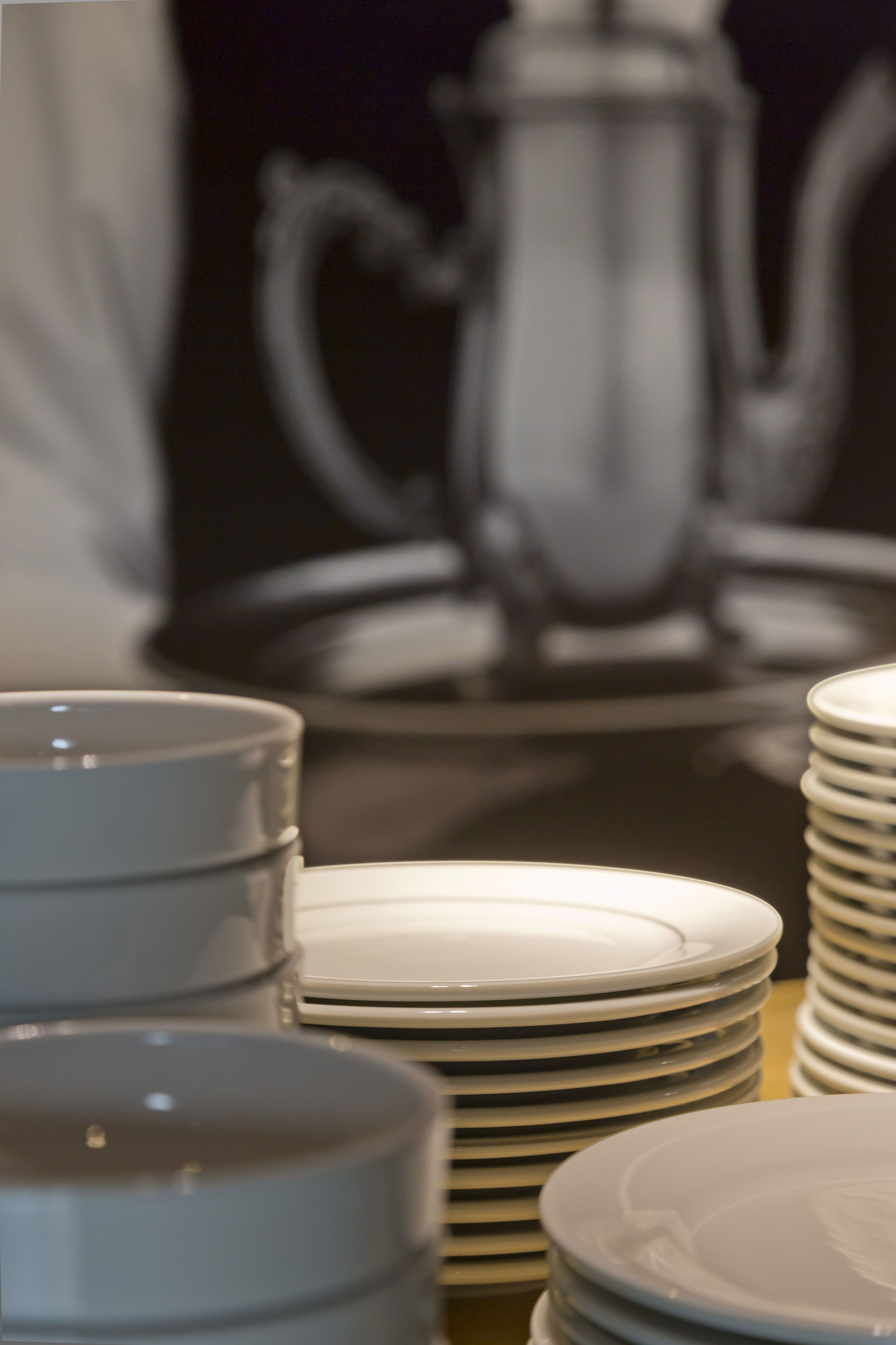 Pilhas de pratos e tigelas brancos sobre uma mesa.