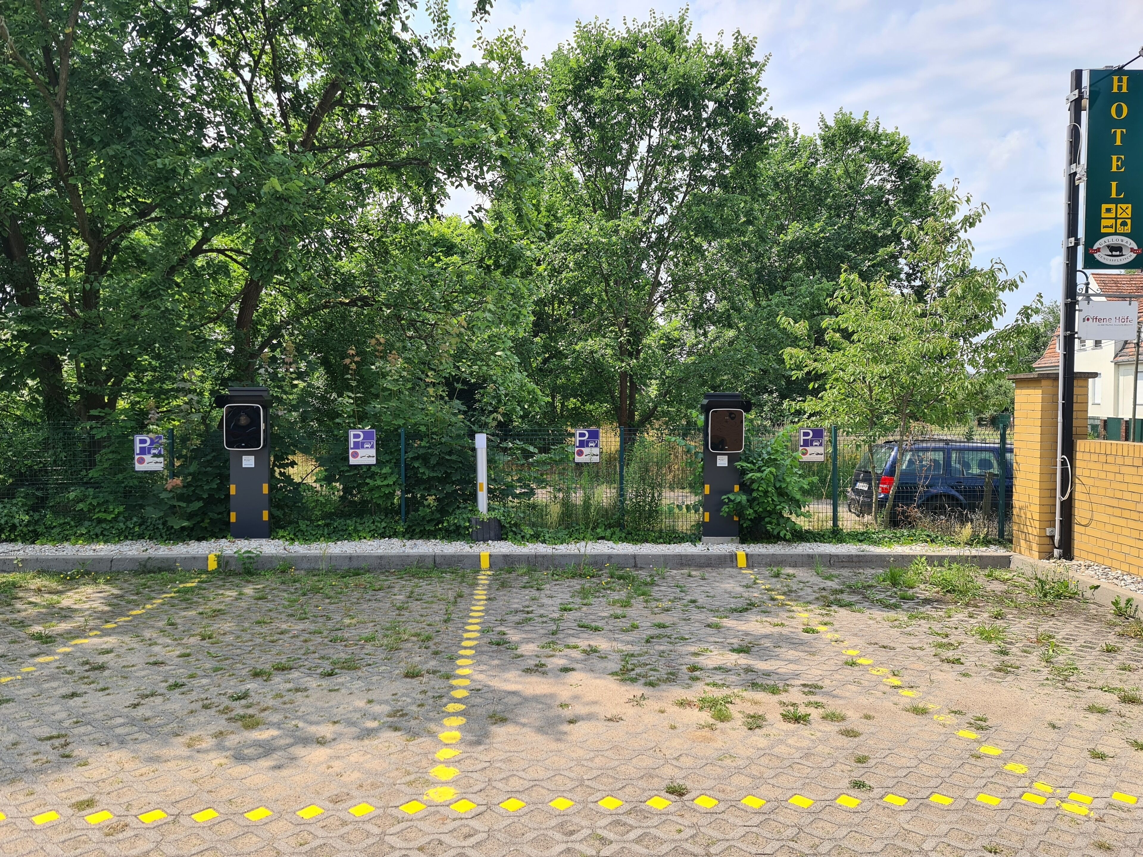 Uma área de estacionamento com vários parquímetros e um letreiro de hotel ao fundo.