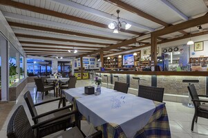 Restaurante com mesas ao ar livre, área de bar e vista para o mar.