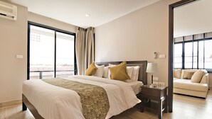 Quarto de hotel com uma cama grande, uma mesa de cabeceira, um abajur e vista para o exterior.