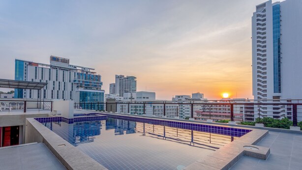 Piscina no terraço com vista para a cidade ao pôr do sol.