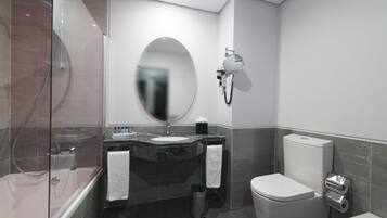 Um banheiro moderno com chuveiro envidraçado, espelho redondo, pia preta e vaso sanitário.