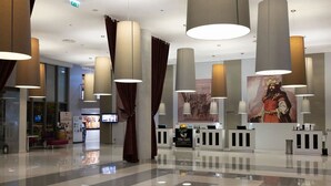 Um lobby de hotel moderno com balcão de recepção, luminárias pendentes grandes e piso polido.