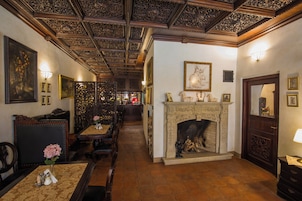 Um quarto com lareira, uma área de jantar com mesa e cadeiras, e um corredor que leva a outro quarto.