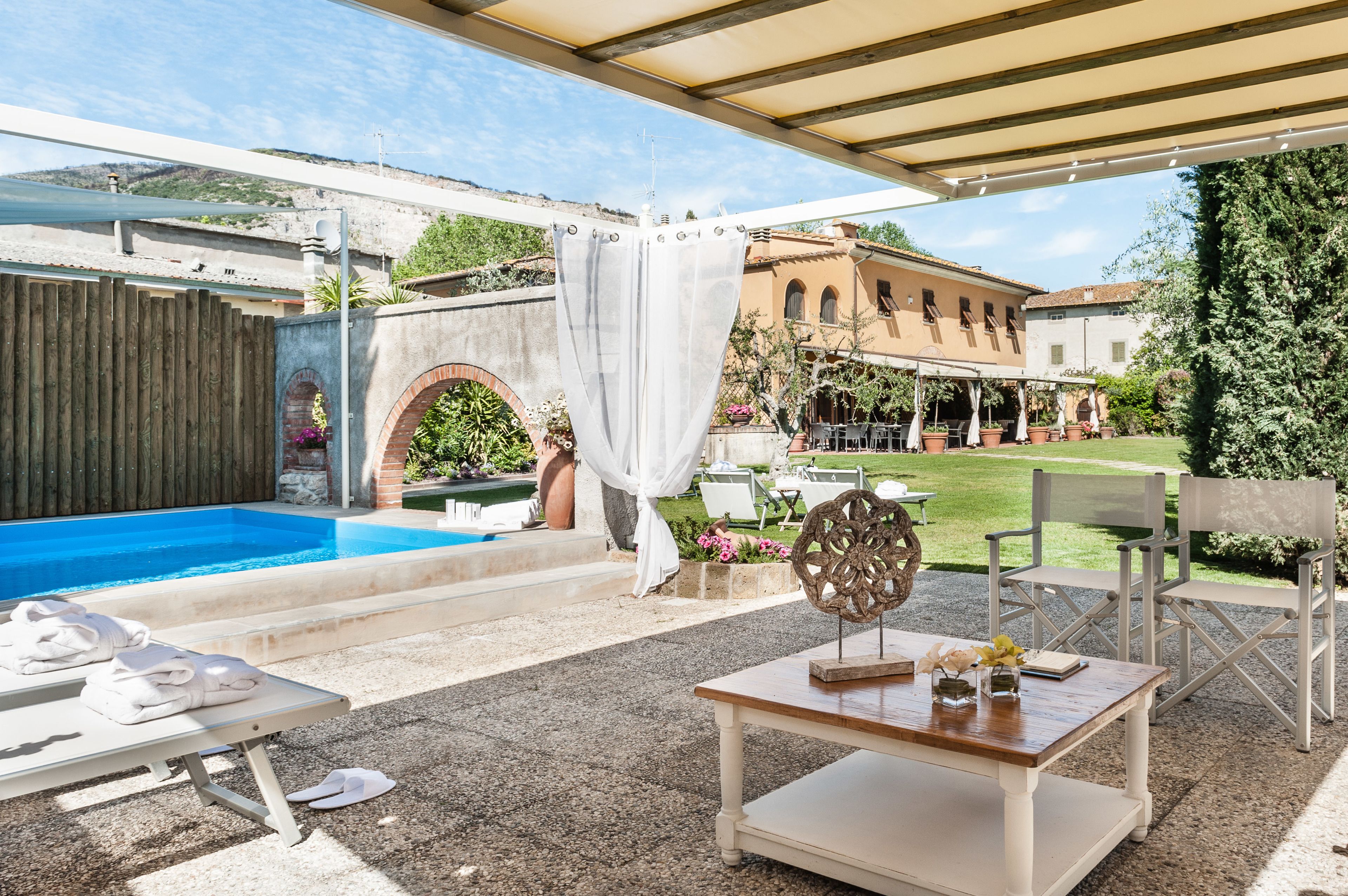 Área de terraço externa com piscina, assentos e área coberta.