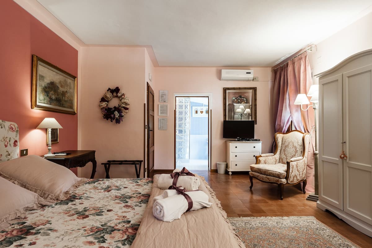 Quarto com cama, cadeira, escrivaninha, televisão e guarda-roupa.