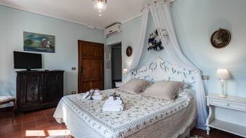 Um quarto com cama, mesa de cabeceira, televisão e guarda-roupa.