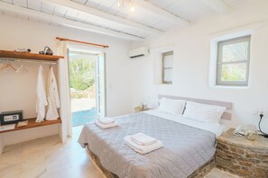 Quarto com uma cama, guarda-roupa, uma pequena mesa e uma janela.