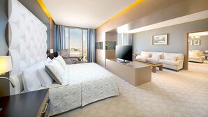 Quarto de hotel moderno com uma cama grande, televisão, sofá e escrivaninha.