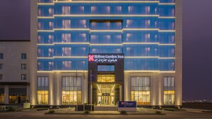 Um Hilton Garden Inn moderno com entrada imponente, janelas amplas e sinalização iluminada.