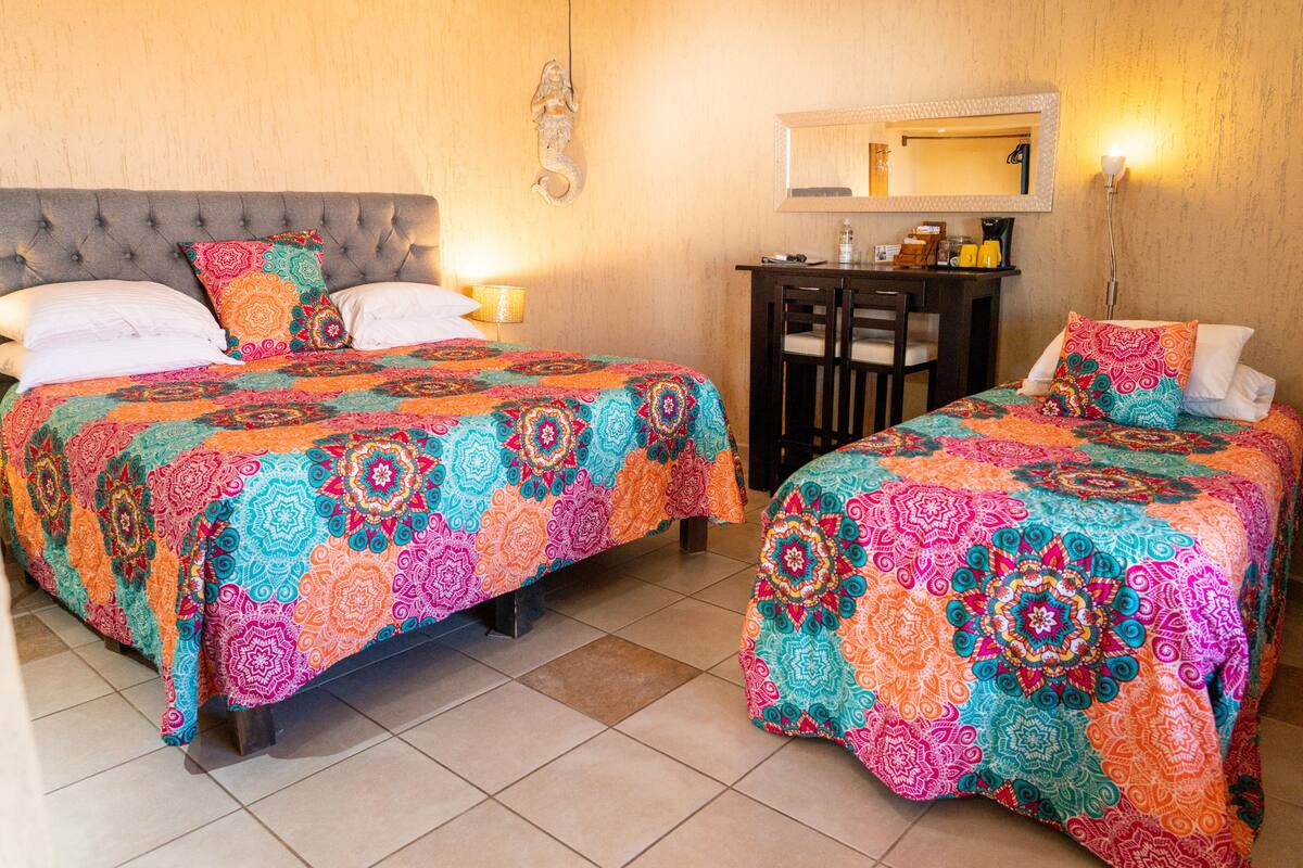Quarto de hotel com duas camas, uma mesa e uma cadeira.