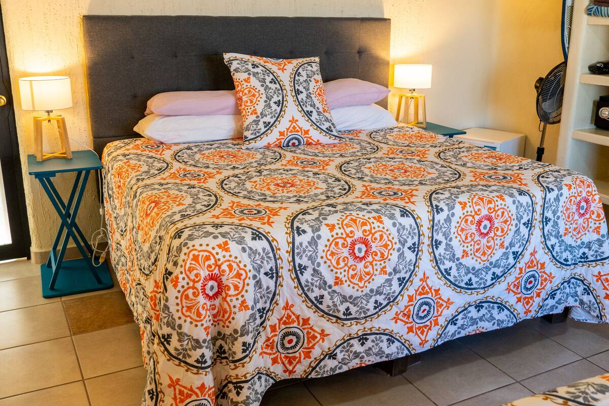 Quarto com cama, mesas de cabeceira, ar condicionado e guarda-roupa.