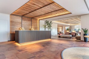 Uma área de recepção moderna com teto de madeira, balcão de atendimento e área de estar com sofás e mesa de centro.