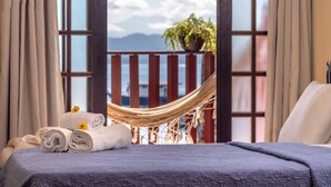 Quarto de hotel com cama, rede e vista para o mar.