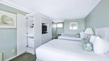 Quarto de hotel com uma cama grande, um guarda-roupa com televisão e uma mesa de cabeceira com abajur.