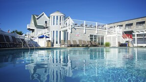 Um hotel com piscina, área coberta com espreguiçadeiras e vista para o oceano.